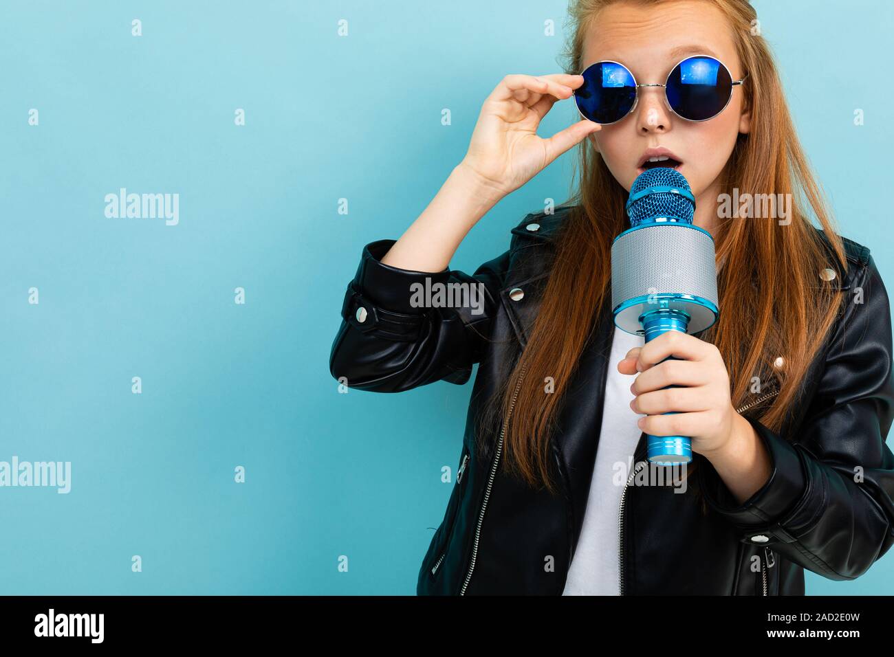 surprised european girl in sunglasses singing with a microphone on a ...