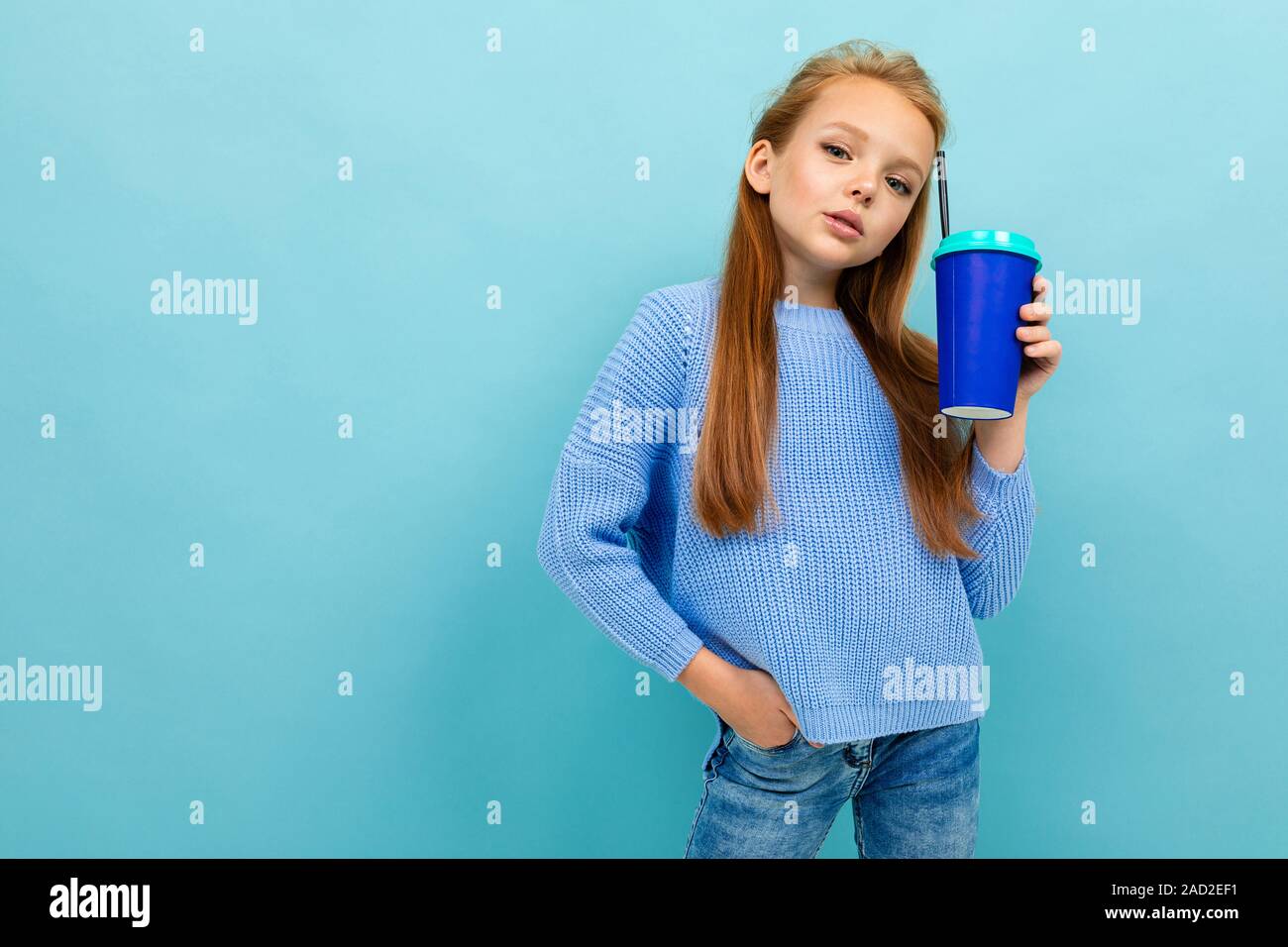 attractive european girl holding a glass in her hands on a light blue ...