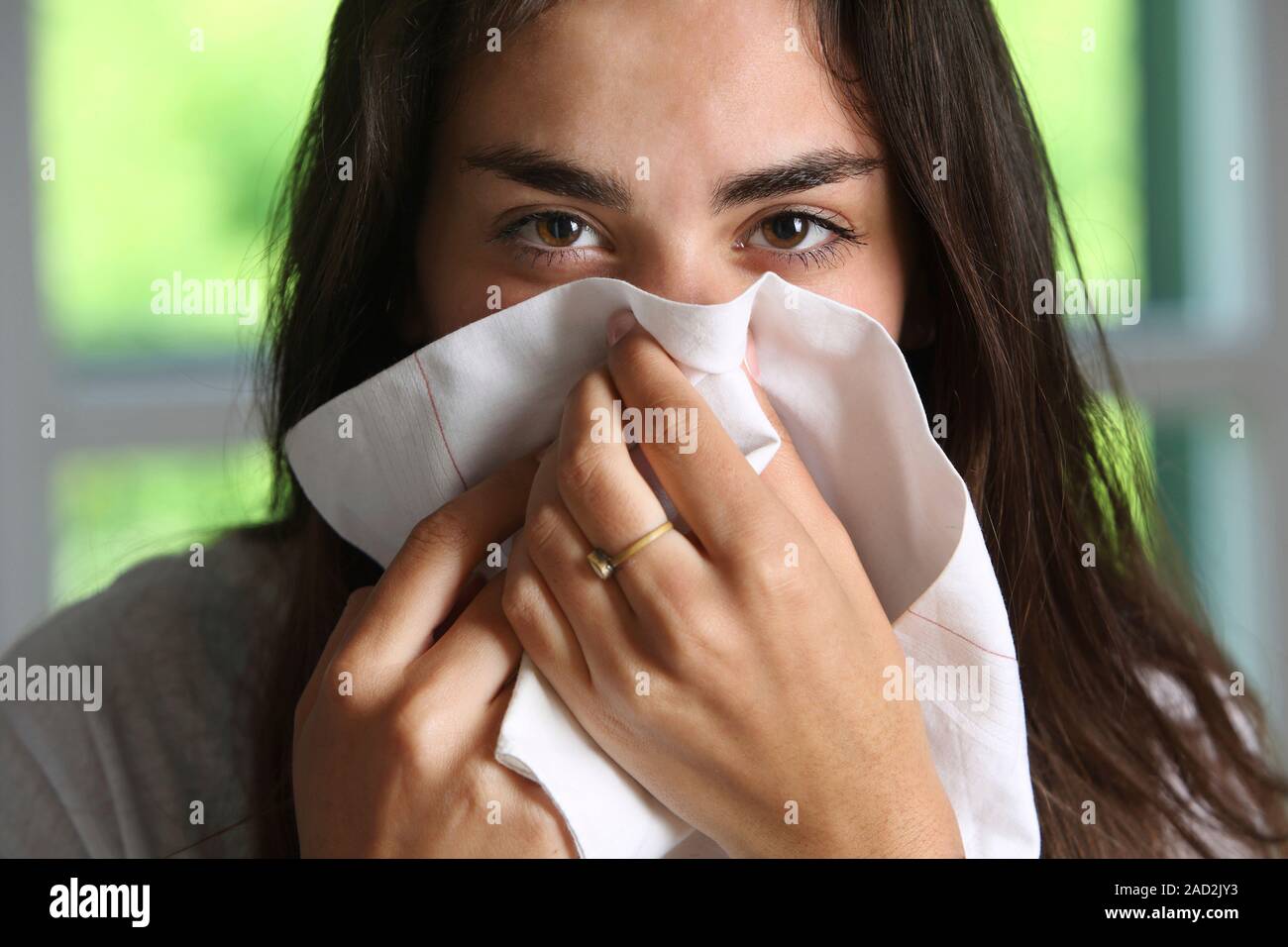 Teenage girl with a cold. 18-year-old girl using a handkerchief to blow ...