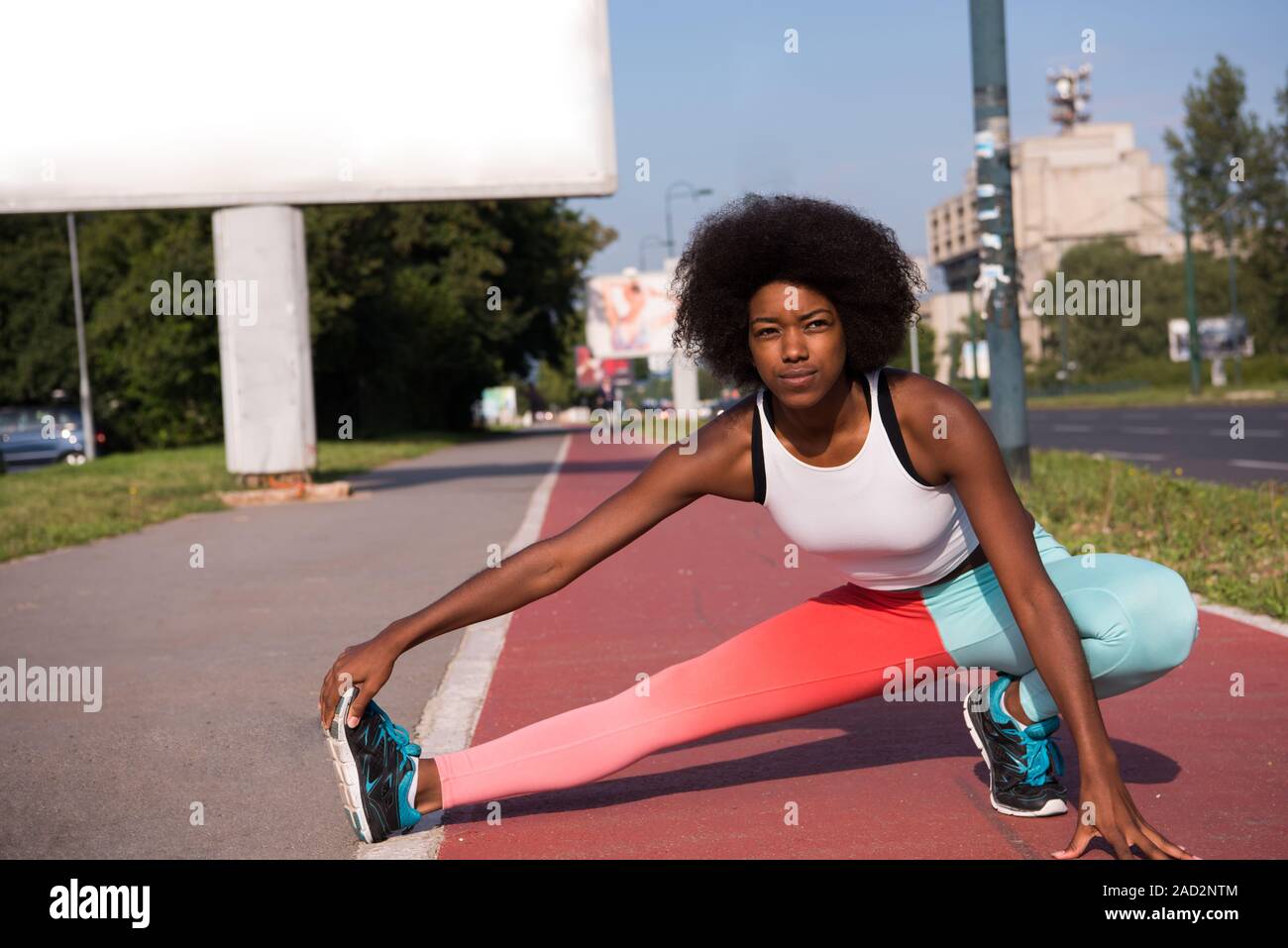 Portrait of sporty young african american woman stretching outdoors ...