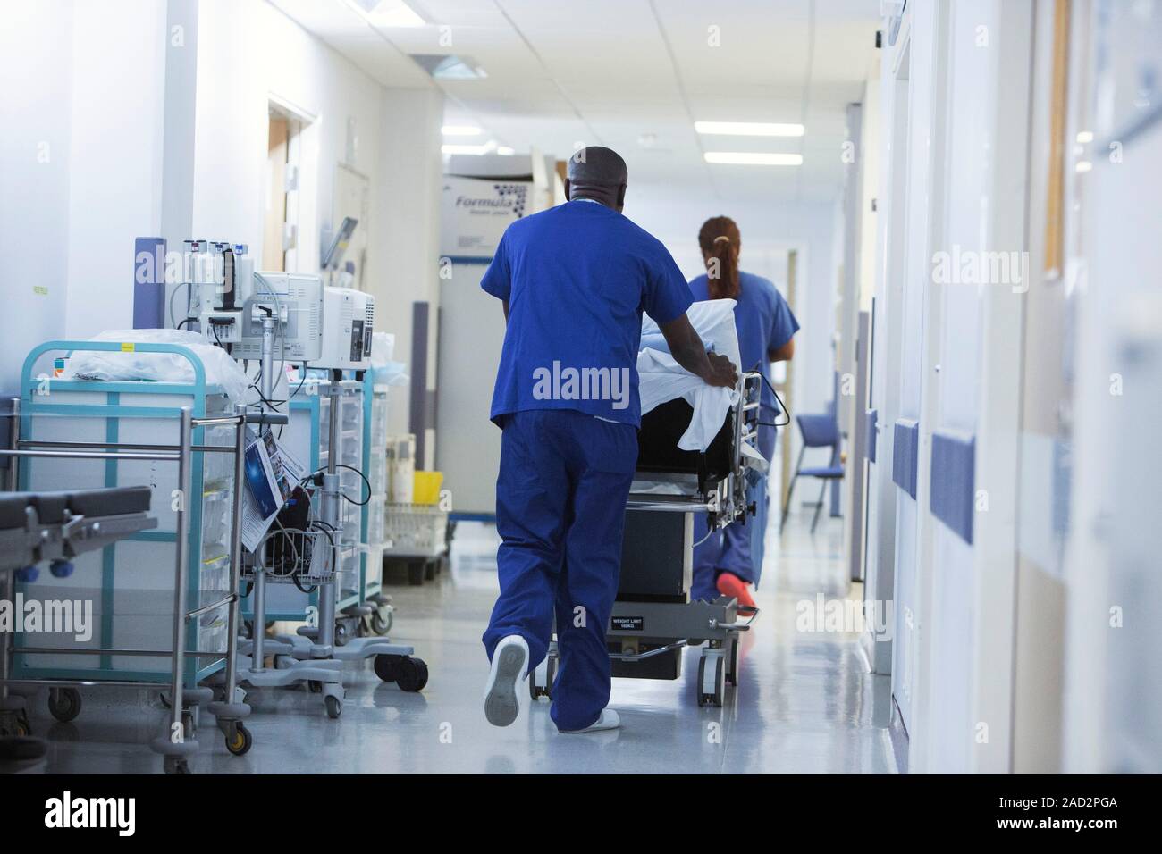 Moving patient in hospital bed. Nurse moving a patient along a corridor ...