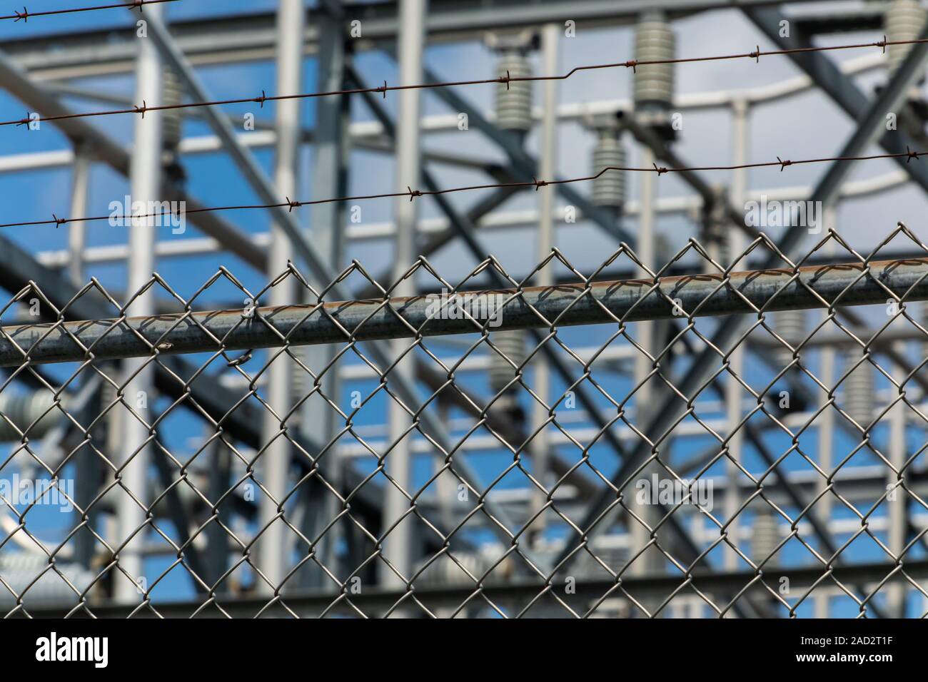 closeup through exterior metal fence electrical substation elements ...
