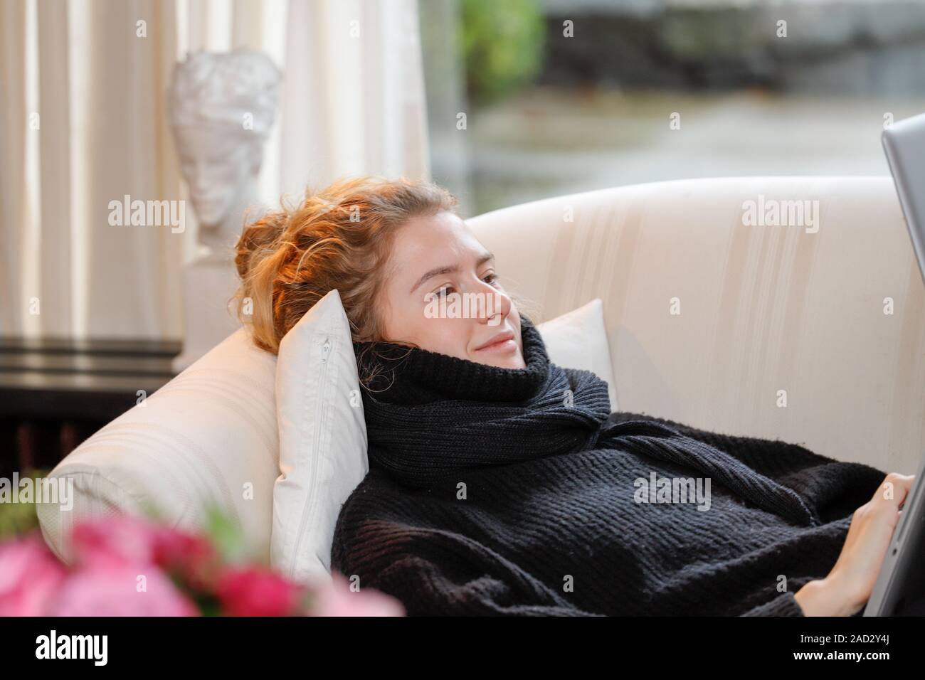 Young attractive law student on a sofa, using notebook and smartphone ...