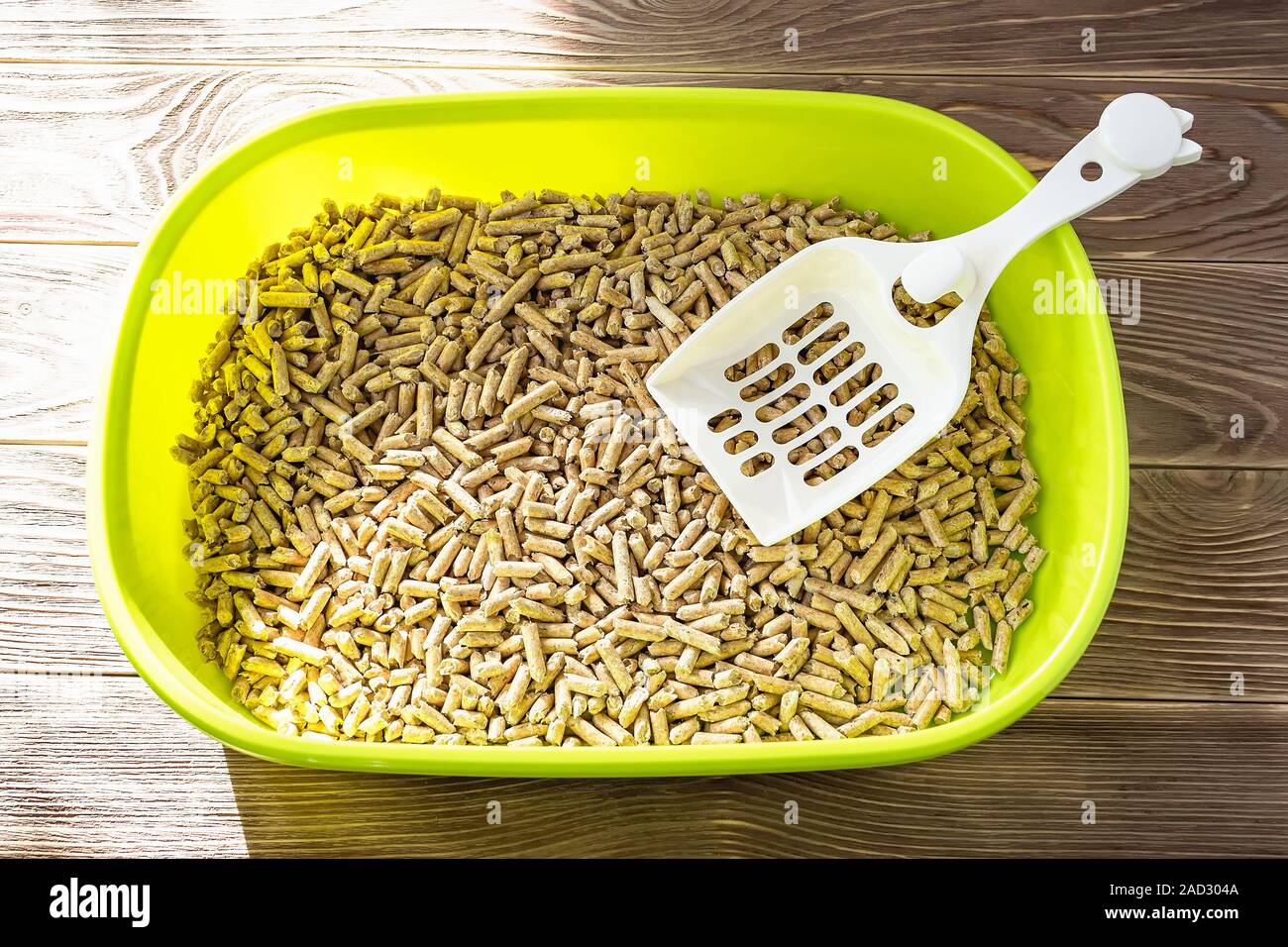 Top view of green cat litter box with wooden pellets and scoop on a ...