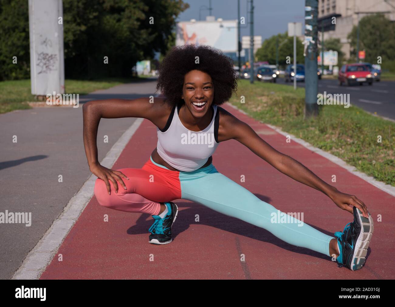 Portrait of sporty young african american woman stretching outdoors ...