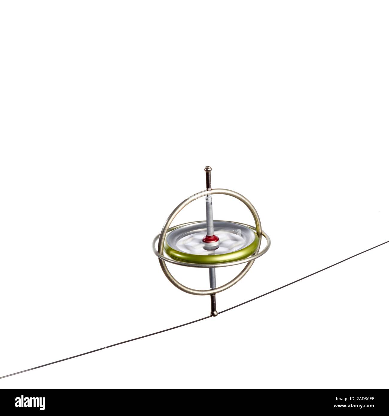 A toy gyroscope balancing on a wire. A gyroscope is a heavy spinning ...