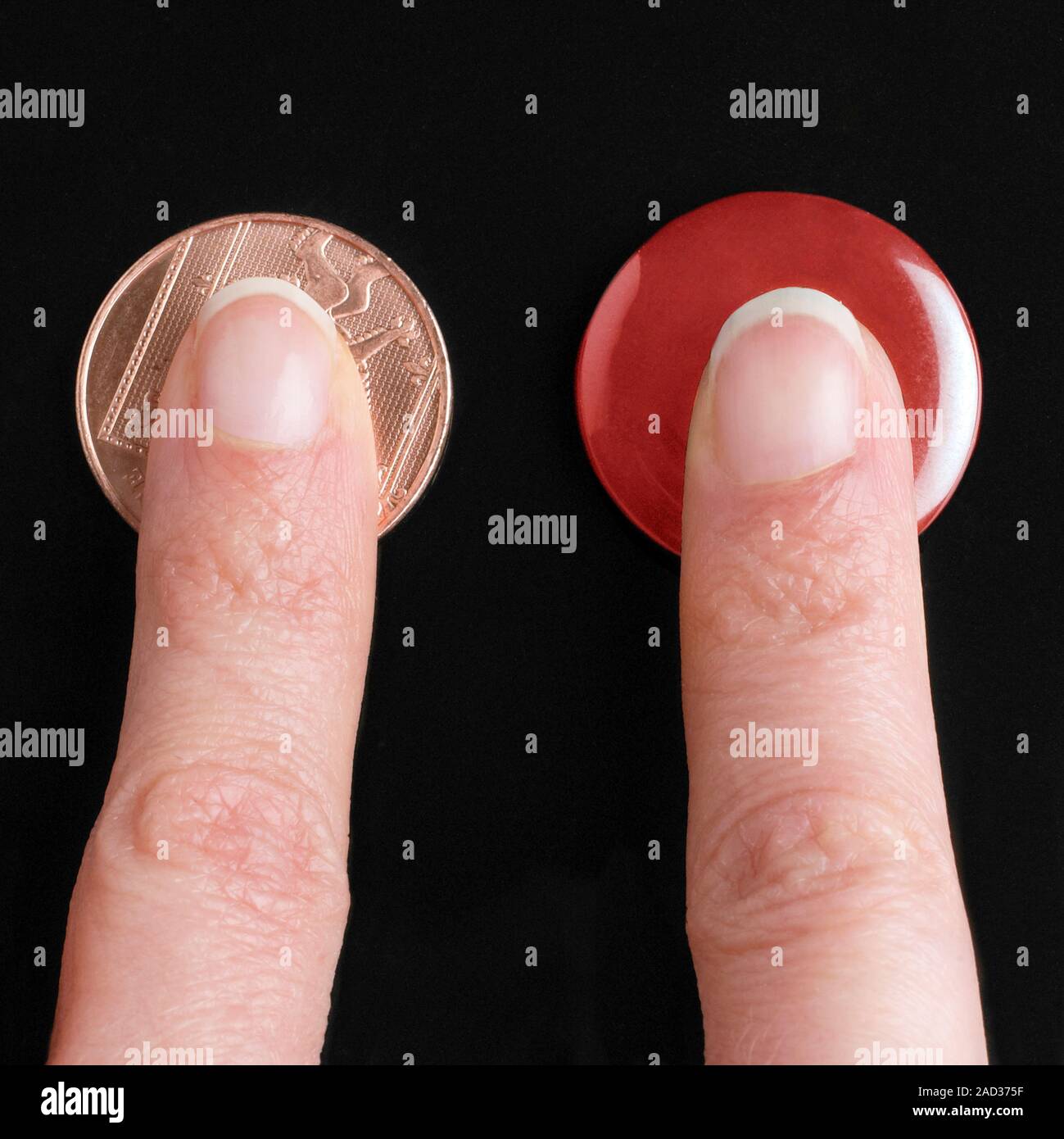 Thermal conduction experiment. A metal coin and a plastic button on ...