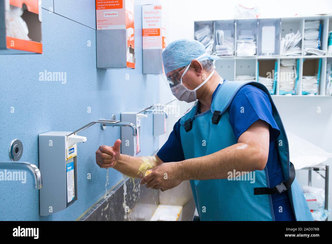 Surgery preparations. Surgeon scrubbing his hands and forearms before a ...