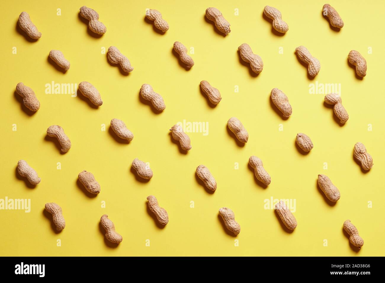 rows of peanuts in shells arranged on yellow paper background - flat ...
