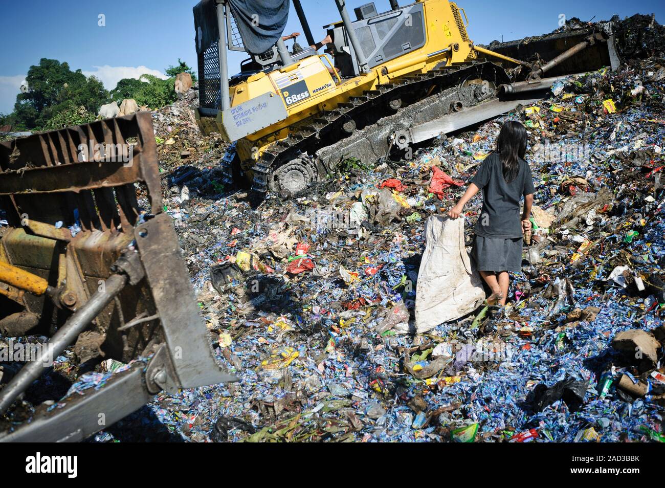 Landfill scavenging. Girl negotiating bulldozers as she searches ...