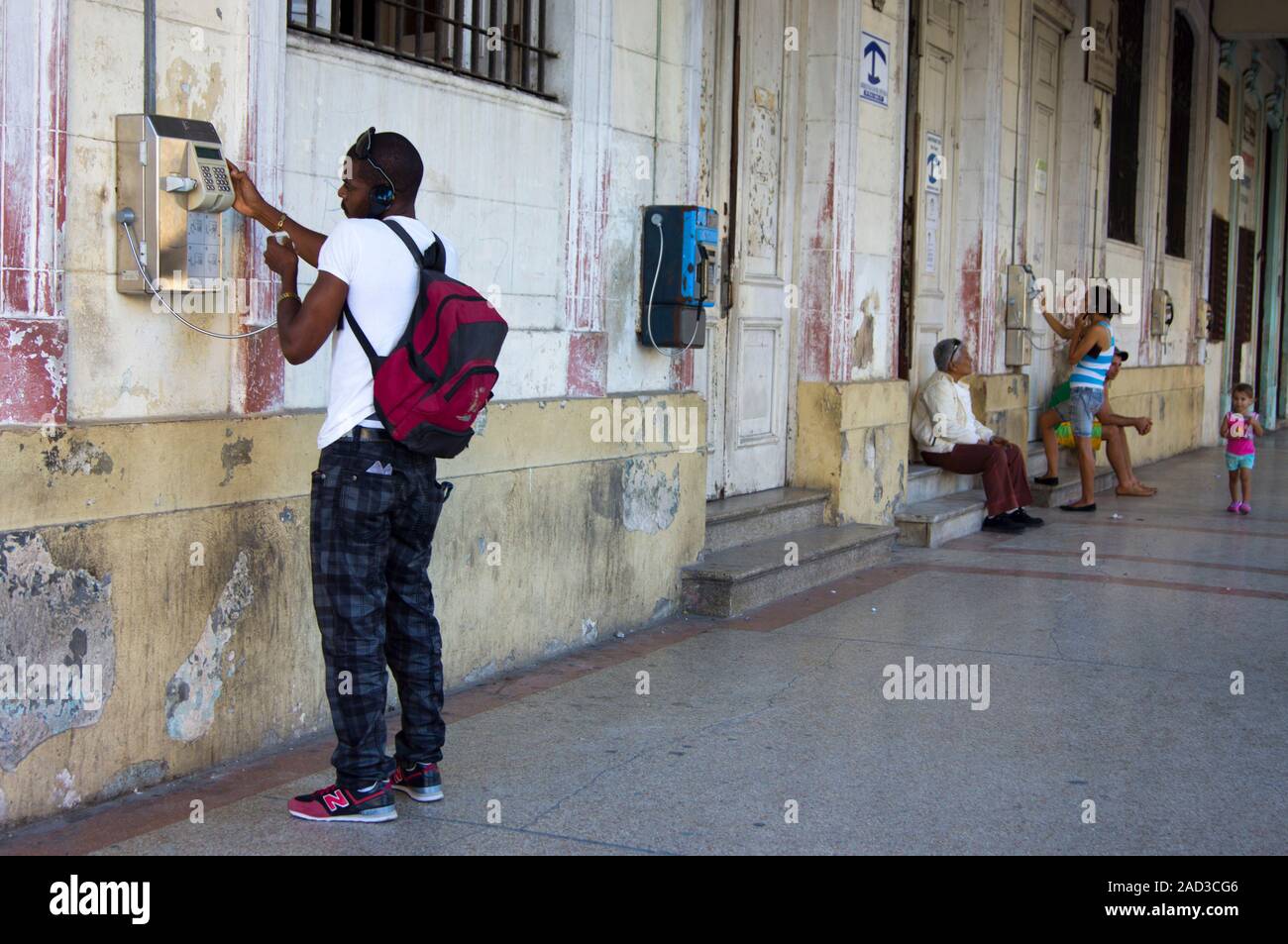 People using wall-mounted public payphones on a street in Havana, Cuba ...