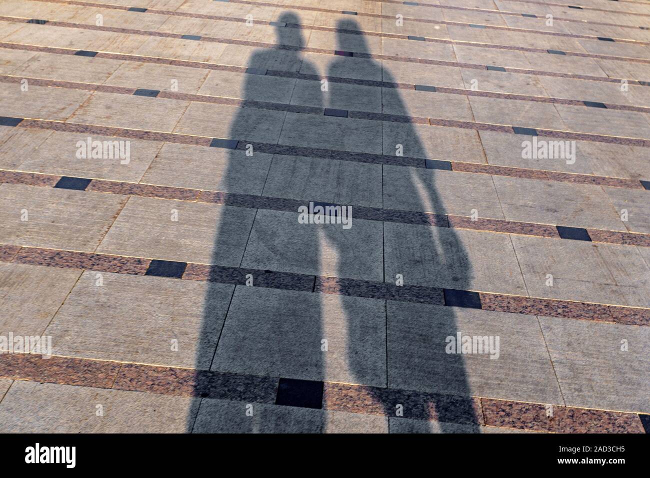 View of shadows of human persons reflected on a paved street. Long ...