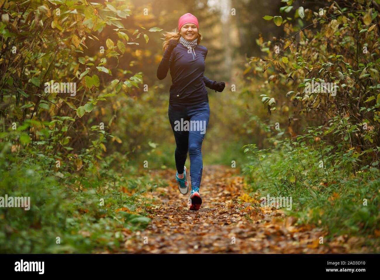 Blond girl running among trees Stock Photo - Alamy