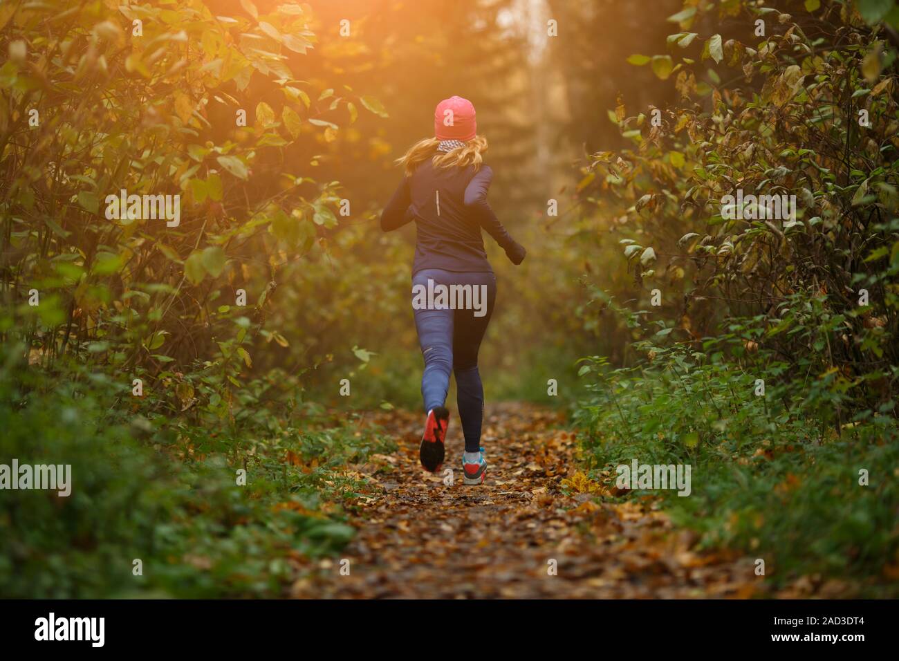 Blonde woman running among trees Stock Photo - Alamy