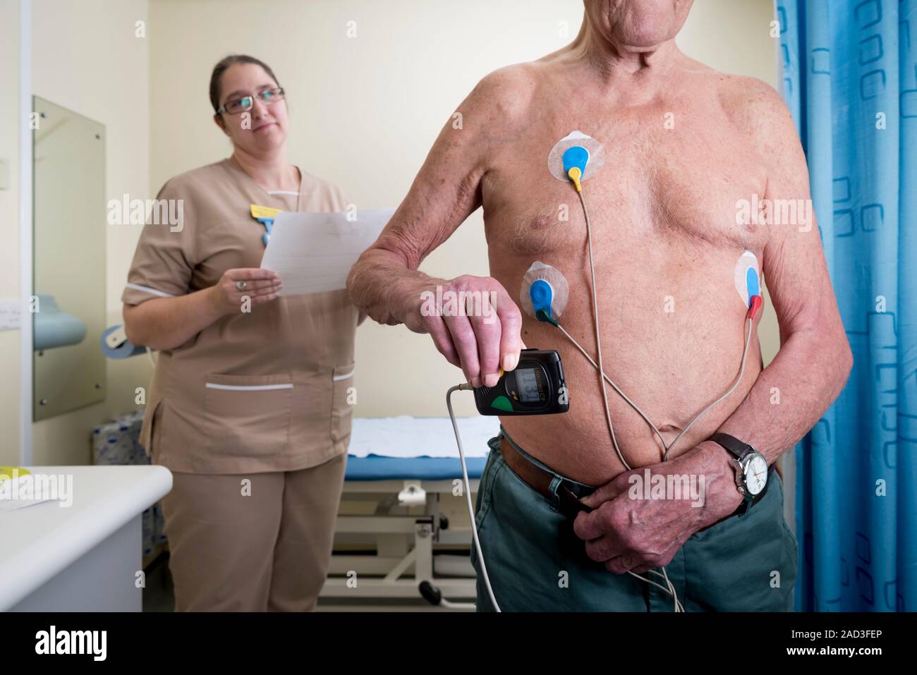 Portable ECG monitor being fitted. Nurse with a patient who is being ...