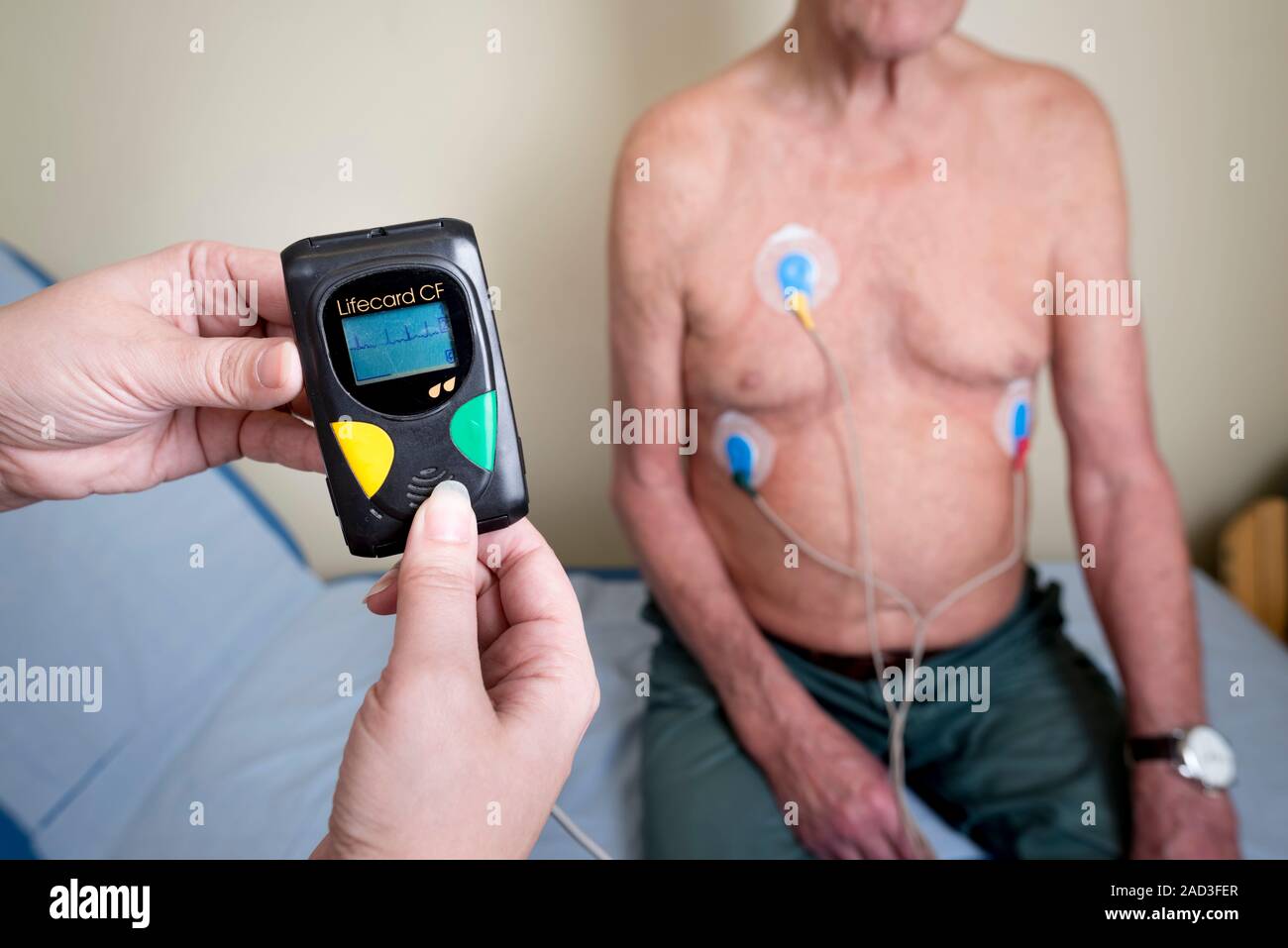 Portable ECG monitor being fitted. Lifecard monitor (left) being held ...