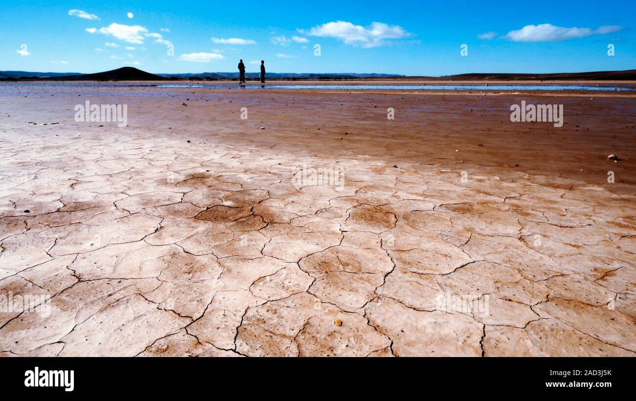 Drying Saharan lake. People standing by the remnants of a lake that is ...