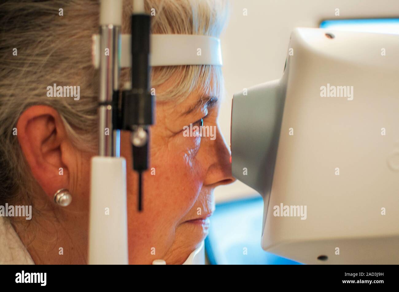 Retinal scan testing for glaucoma. Woman with her head resting in a ...