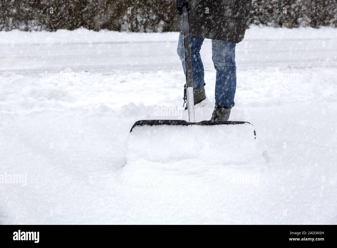 Woman clearing snow on sidewalk Stock Photo - Alamy