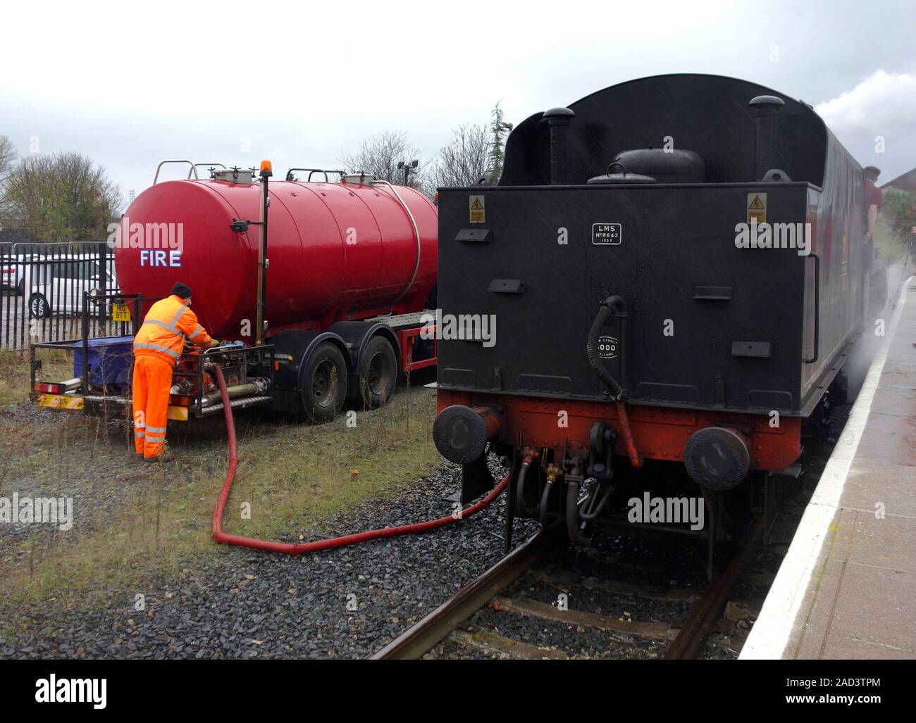 Steam train. A railway worker replenishes the boiler of a steam ...