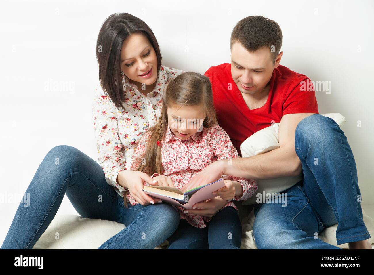 Happy family. Parents reading book with daughter Stock Photo - Alamy