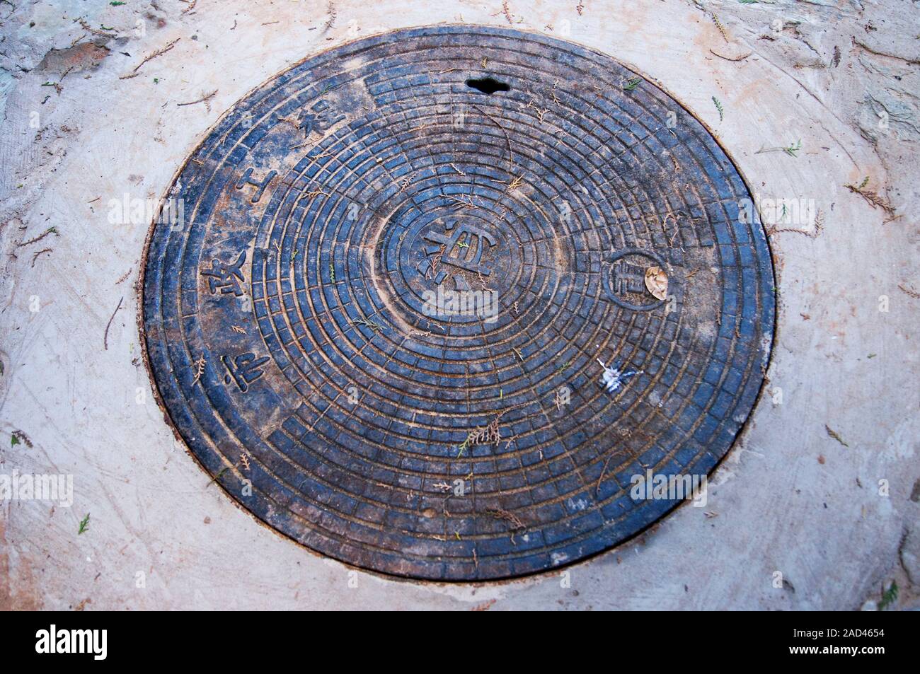 A manhole cover in Beijing, China, with Chinese characters on a ...