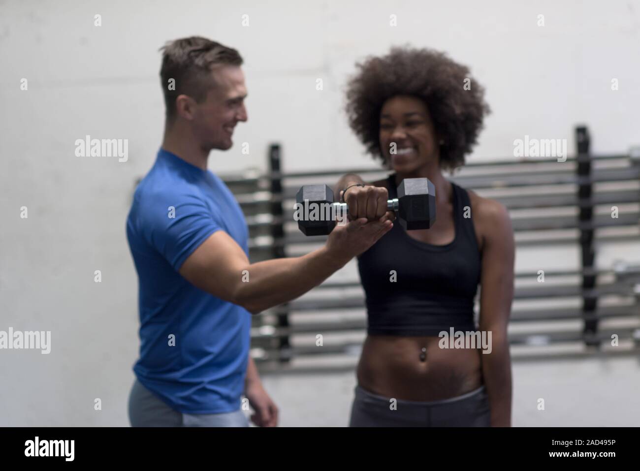 black woman doing bicep curls with fitness trainer Stock Photo - Alamy