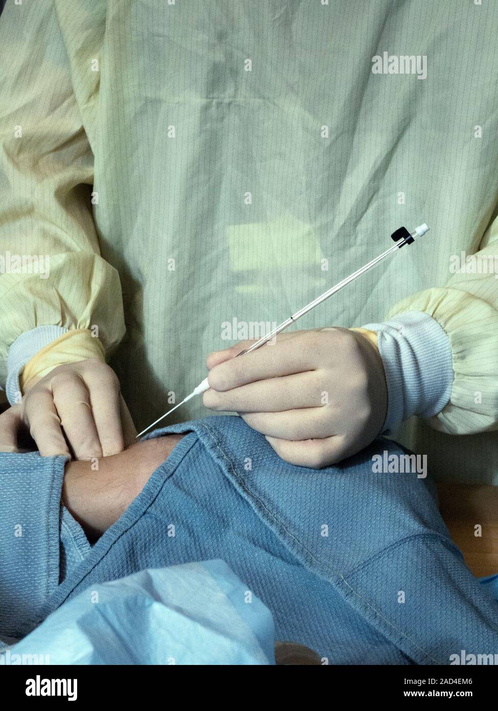 Arterial catheterisation. Surgeon in an intensive care unit preparing ...
