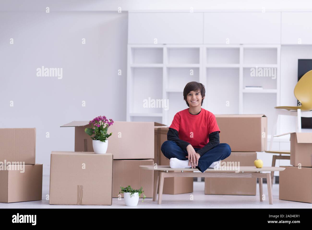 boy sitting on the table with cardboard boxes around him Stock Photo ...