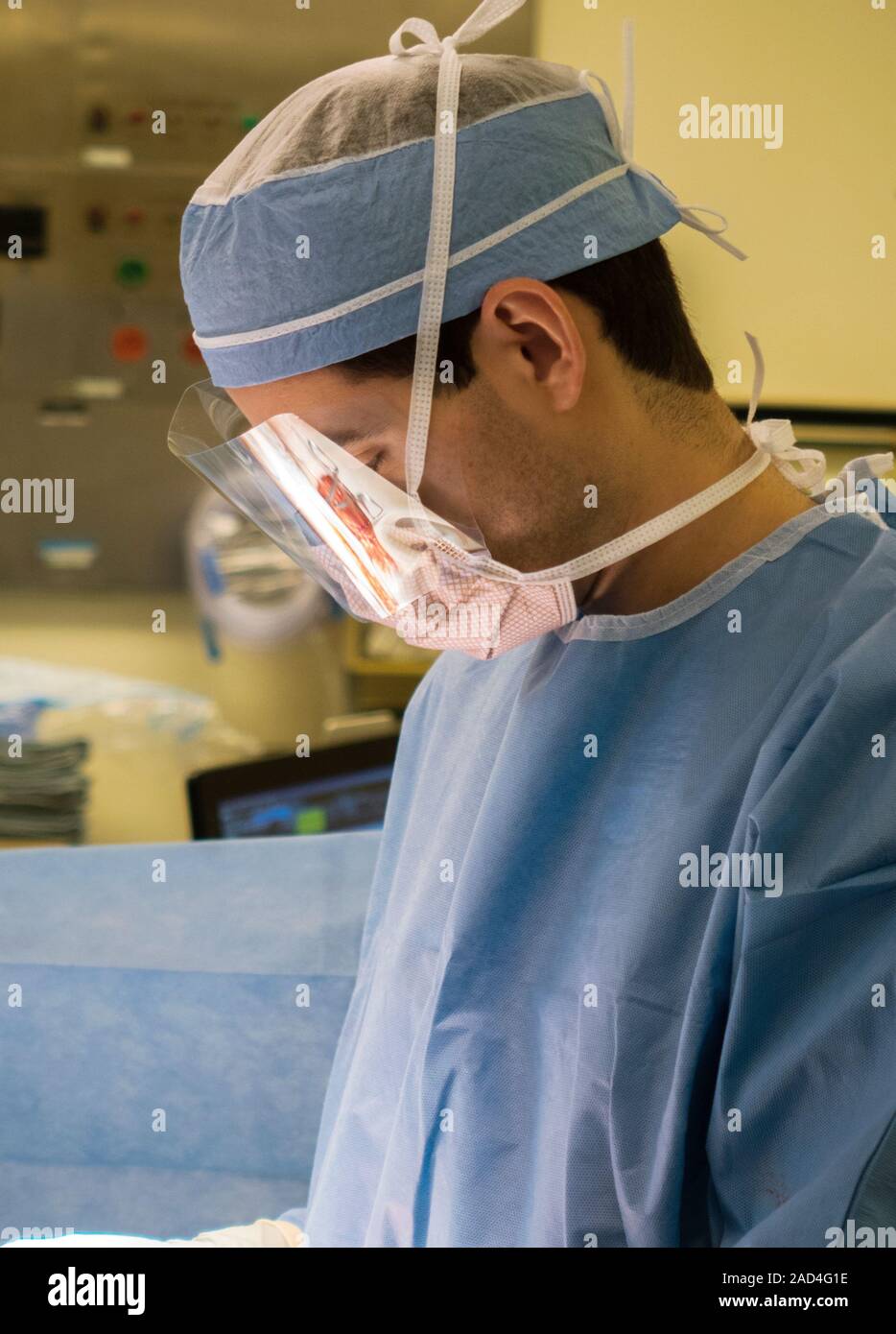 Surgeon operating. Surgeon wearing a face-shield whilst operating on a ...