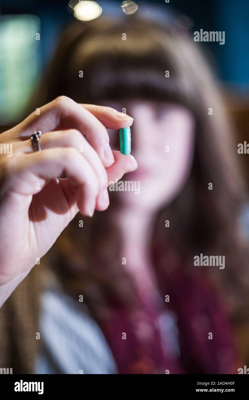 Student testing drugs. University student holding a drug capsule that ...
