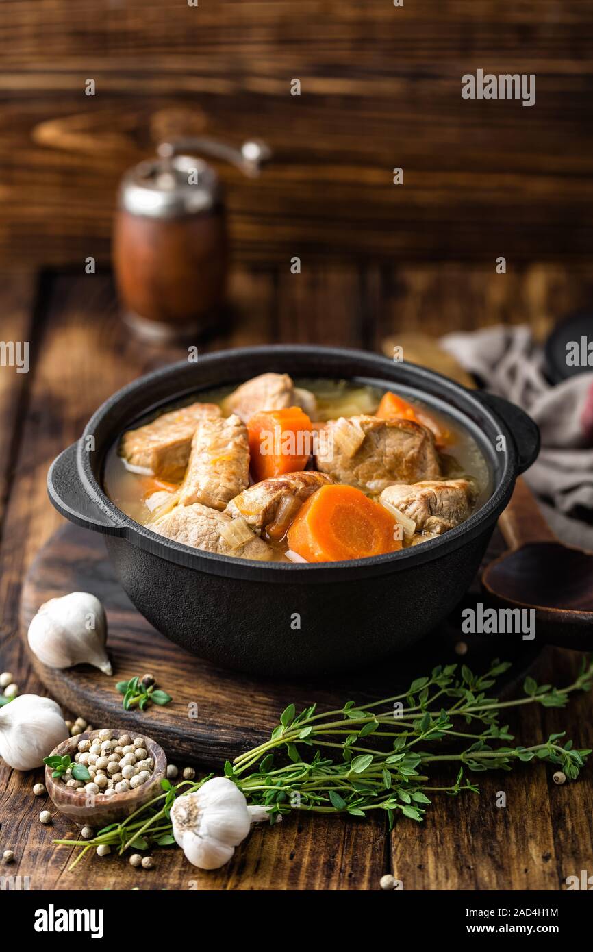 Meat stewed with carrots in sauce and spices in cast iron pot on dark ...