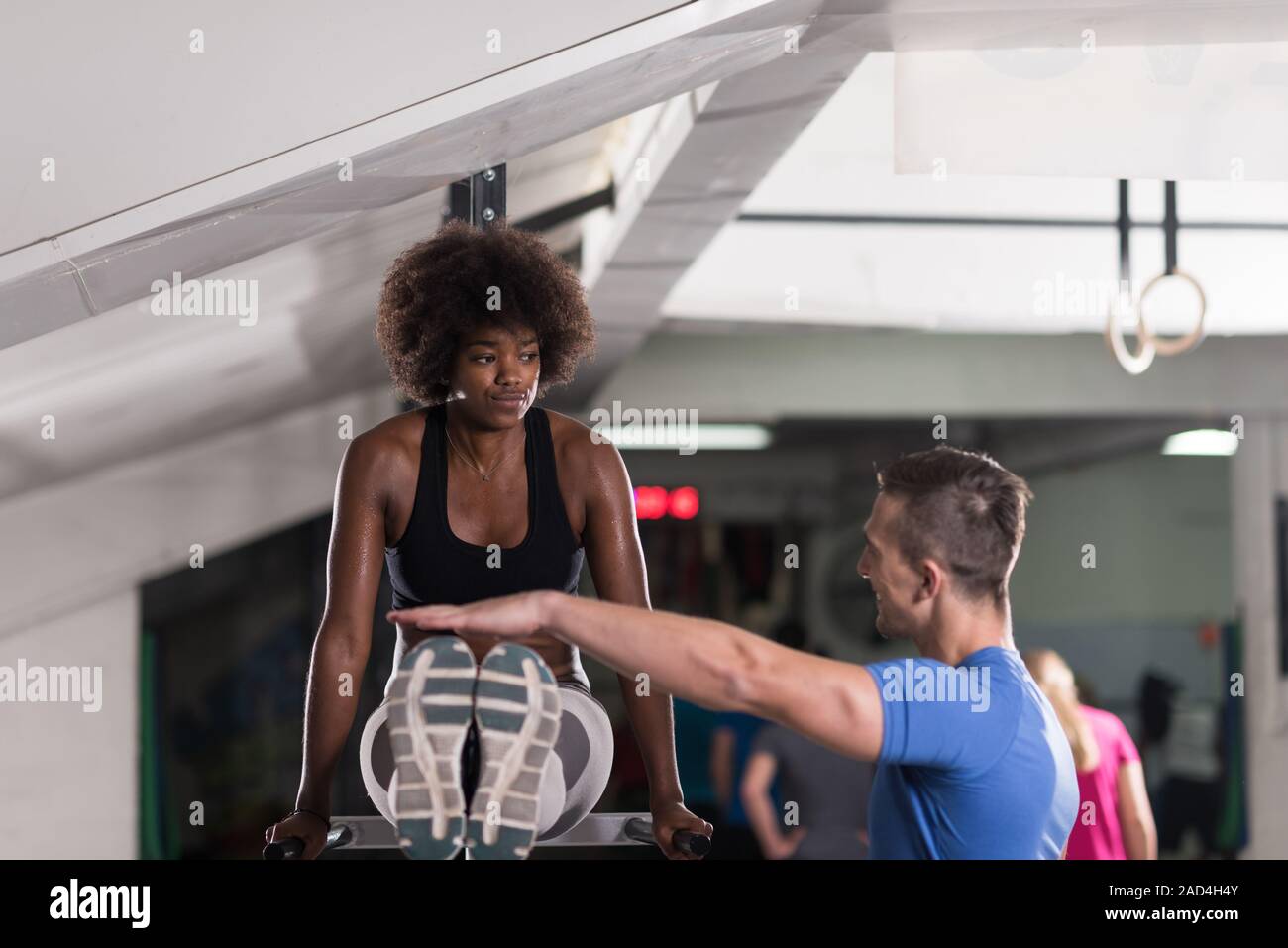 black woman doing parallel bars Exercise with trainer Stock Photo - Alamy