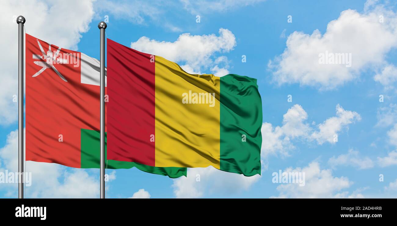 Oman and Guinea flag waving in the wind against white cloudy blue sky ...