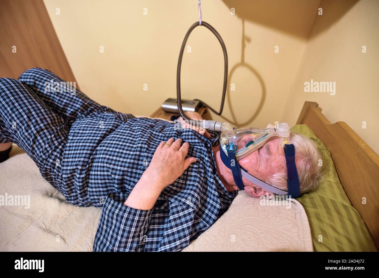 Sleep apnoea treatment. Male patient using a continuous positive airway ...