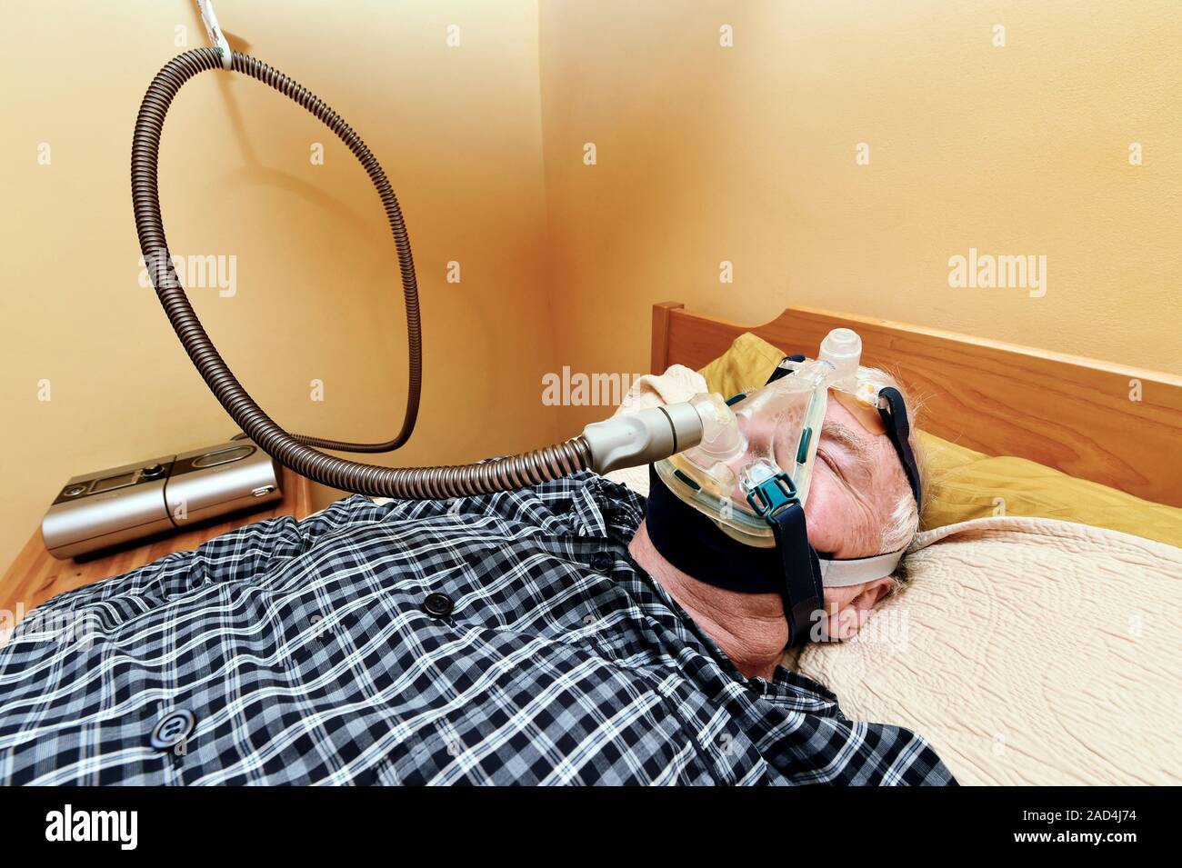 Sleep apnoea treatment. Male patient using a continuous positive airway ...