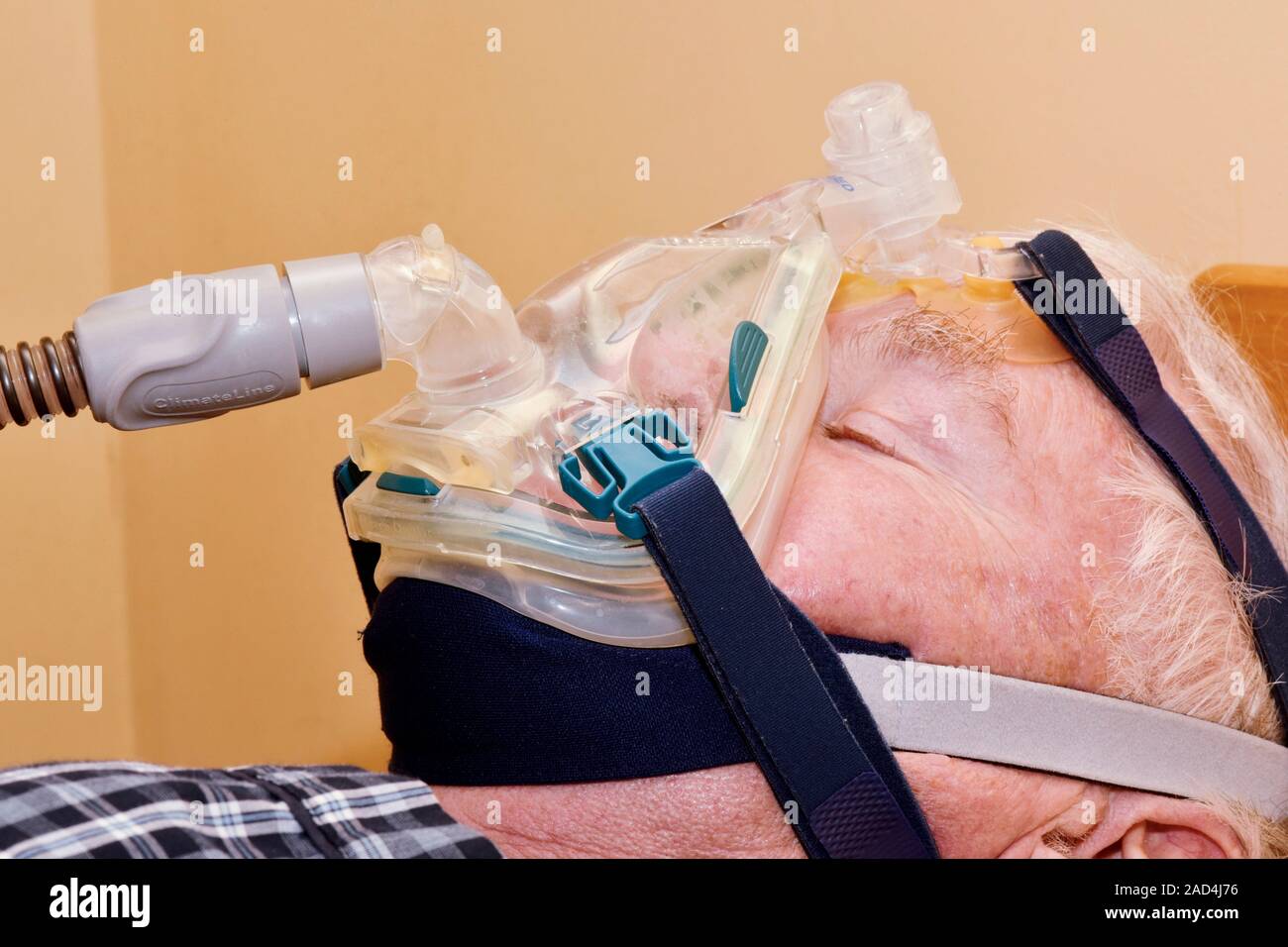 Sleep apnoea treatment. Male patient using a continuous positive airway ...