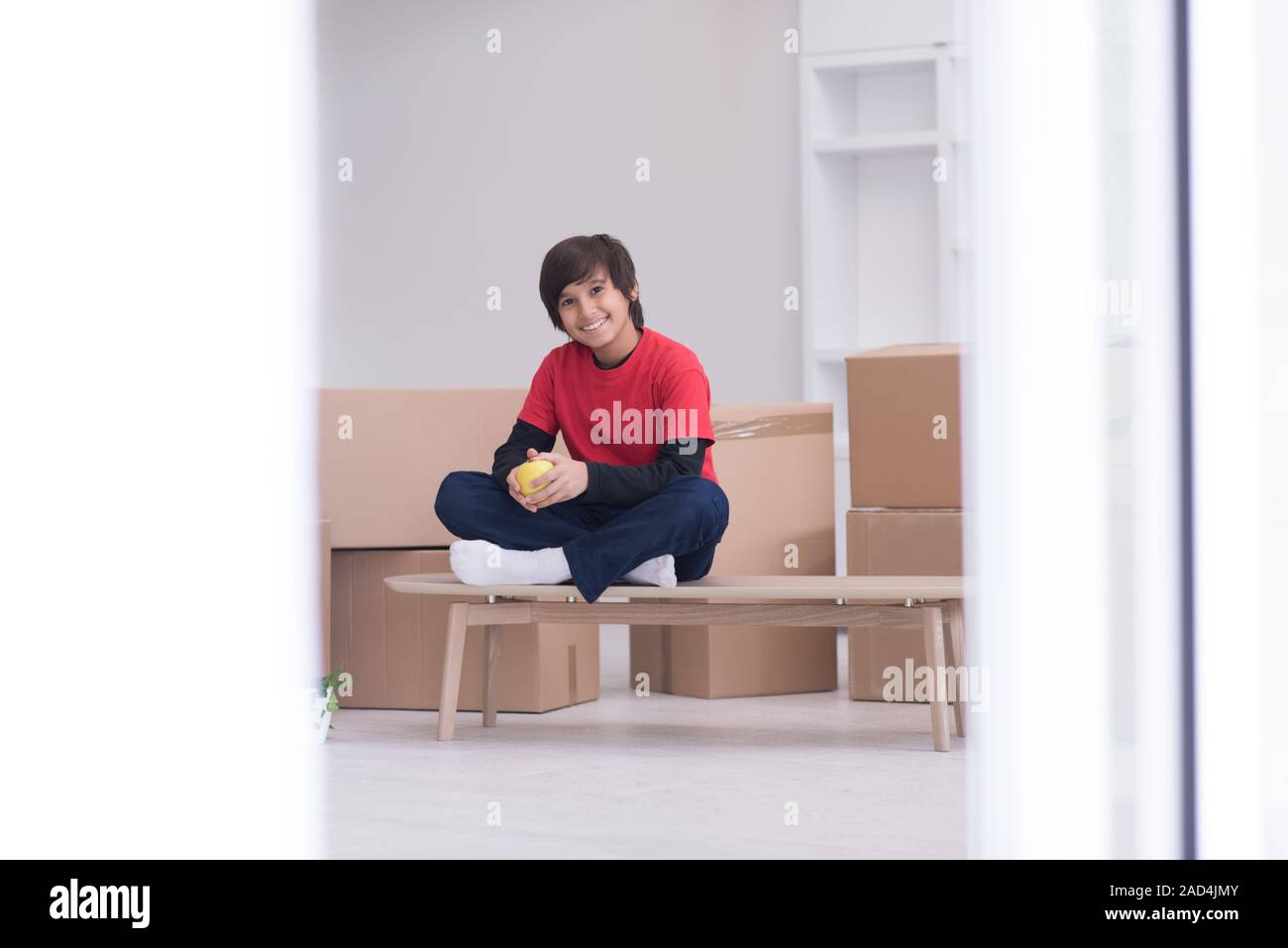 boy sitting on the table with cardboard boxes around him Stock Photo ...