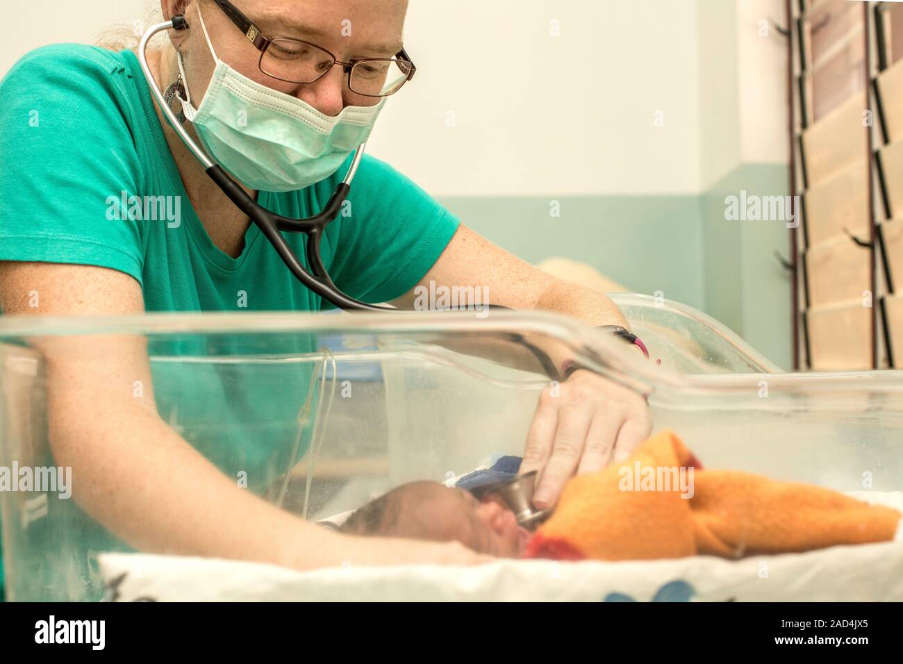 Hospital doctor with newborn baby, using a stethoscope to assess the ...