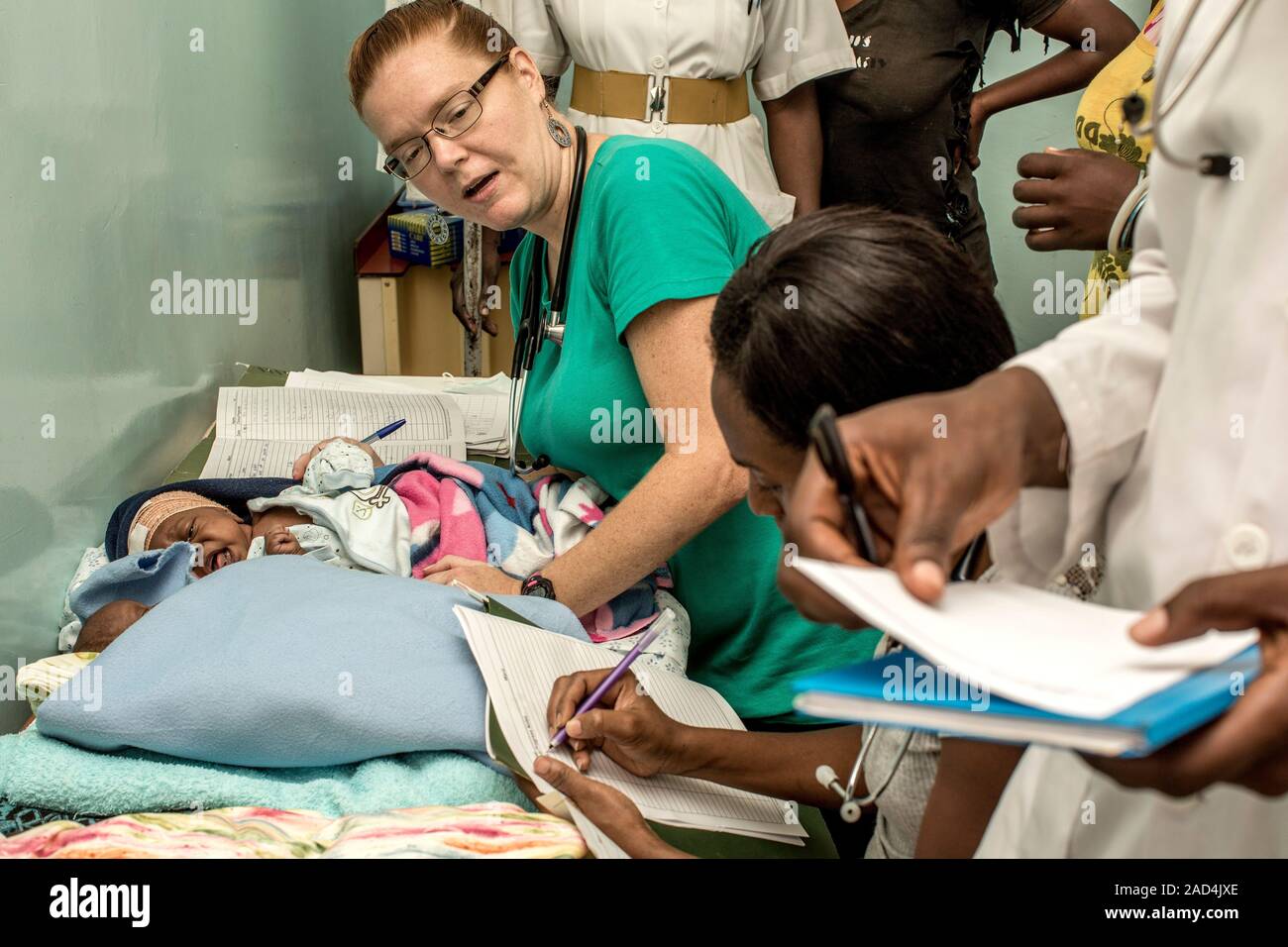 Hospital doctors examining babies, and making notes on their health ...