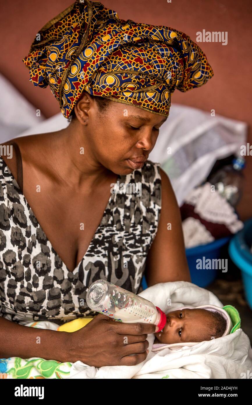 Mother bottle-feeding her baby. Photographed in Lacor, Gulu, Uganda ...
