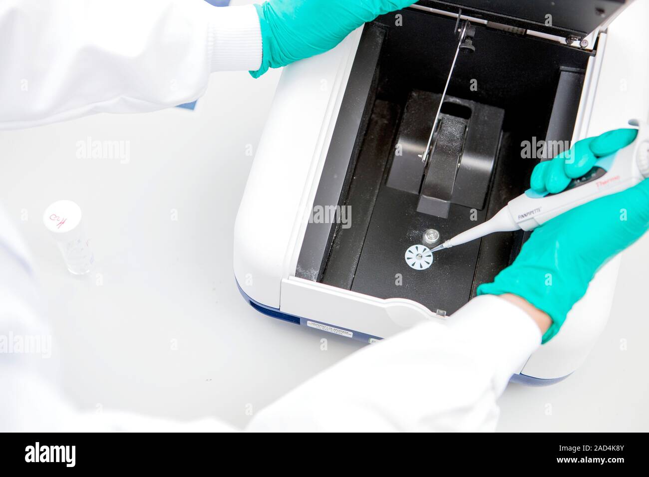 Spectrophotometer analysis. Researcher using a pipette to add a sample ...