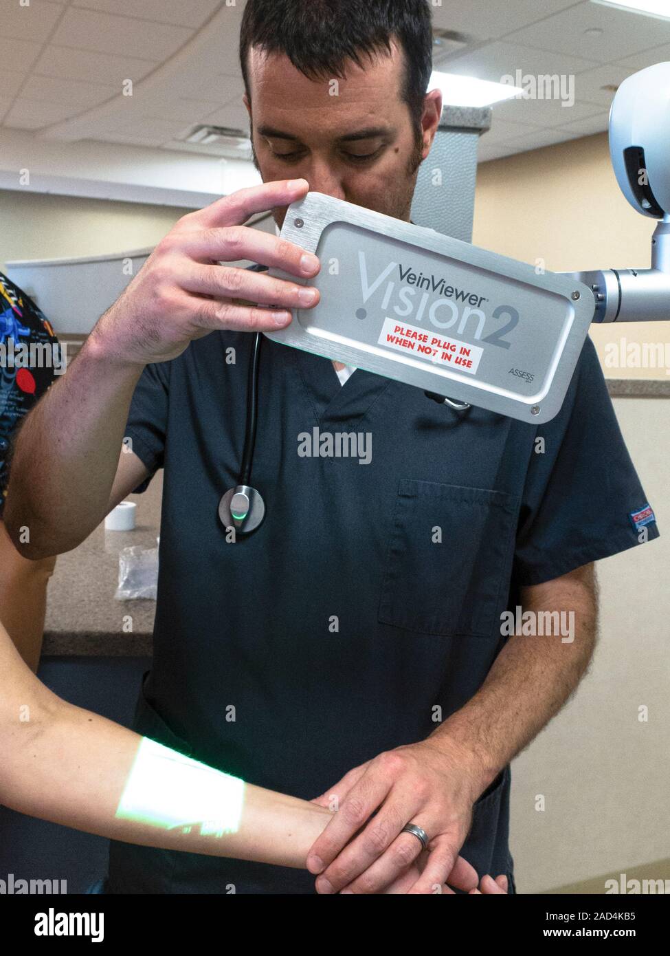 Infrared vein-finding device. Nurse demonstrating the use of an ...