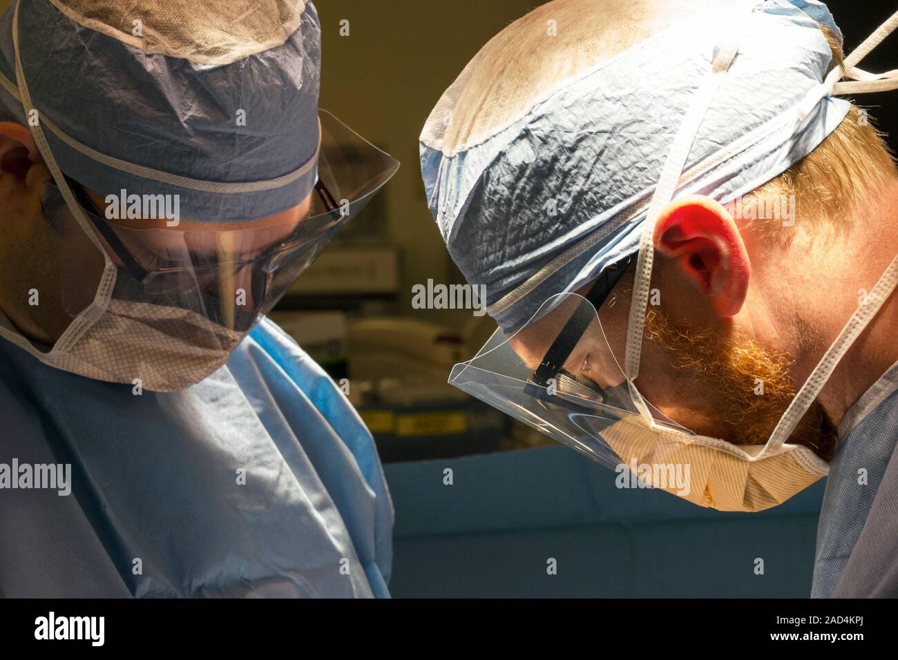 Surgeons wearing visors, face masks and surgical drapes during surgery ...