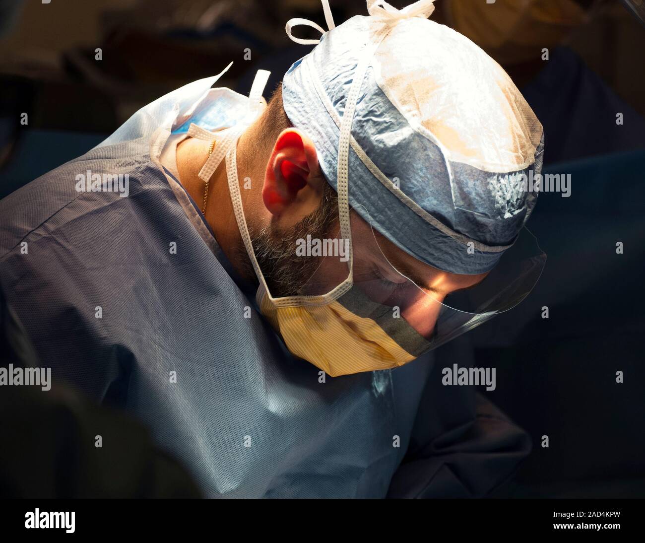 Surgeon wearing a visor, a face mask and surgical drapes during surgery ...