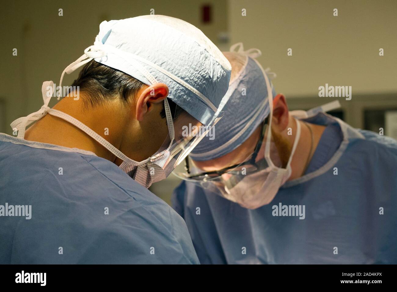 Surgeons wearing visors, face masks and surgical drapes during surgery ...