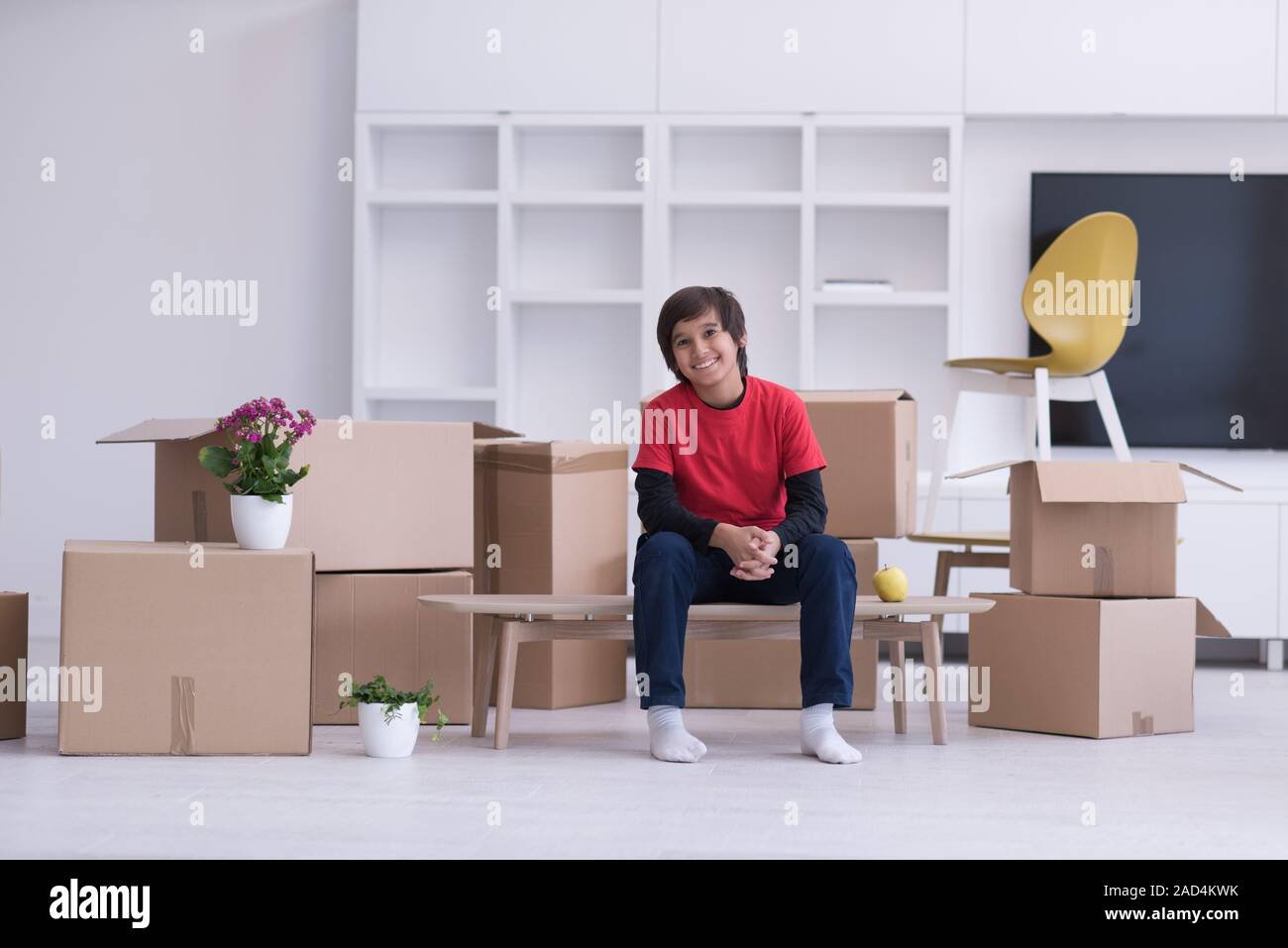 boy sitting on the table with cardboard boxes around him Stock Photo ...