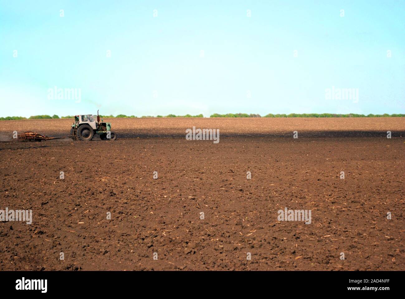 Tractor sow grain in the field of black earth, sunny blue sky, Ukraine ...