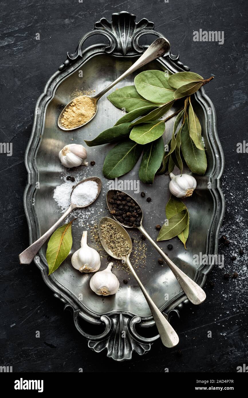 Dark culinary background with bay leaves, salt, pepper and garlic Stock ...