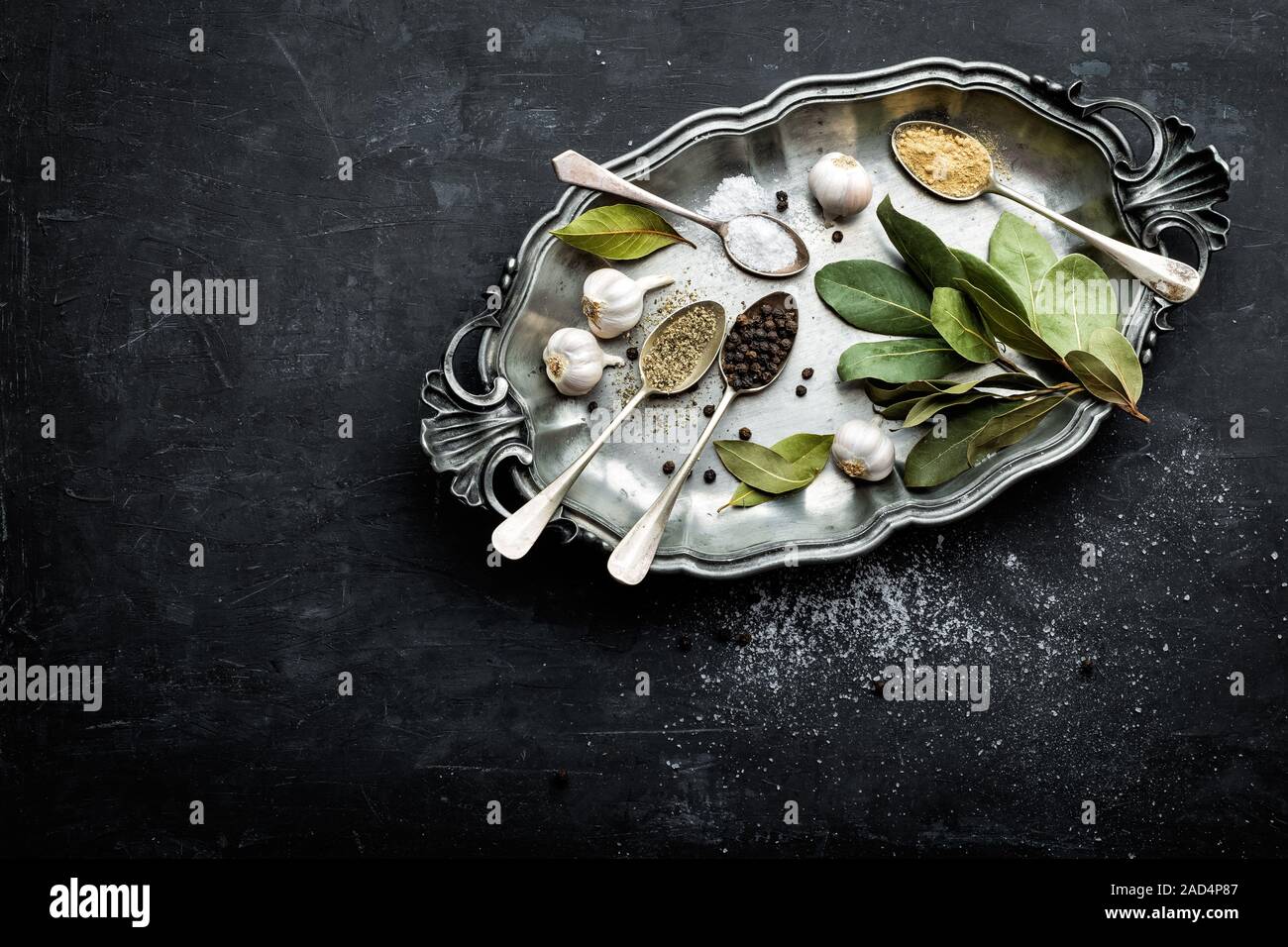 Dark culinary background with bay leaves, salt, pepper and garlic Stock ...
